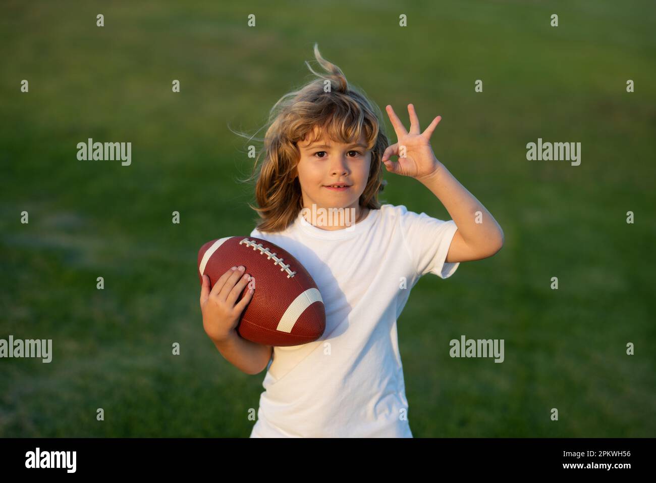 American football. Kid boy playing with rugby ball in park. Child ready ...
