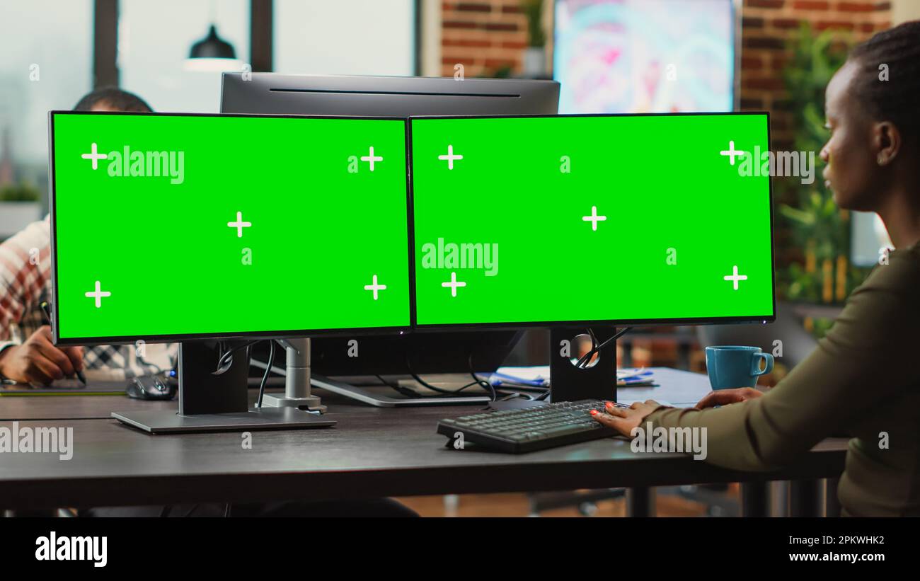 Young digital creator looking at computers with greenscreen, working on ...