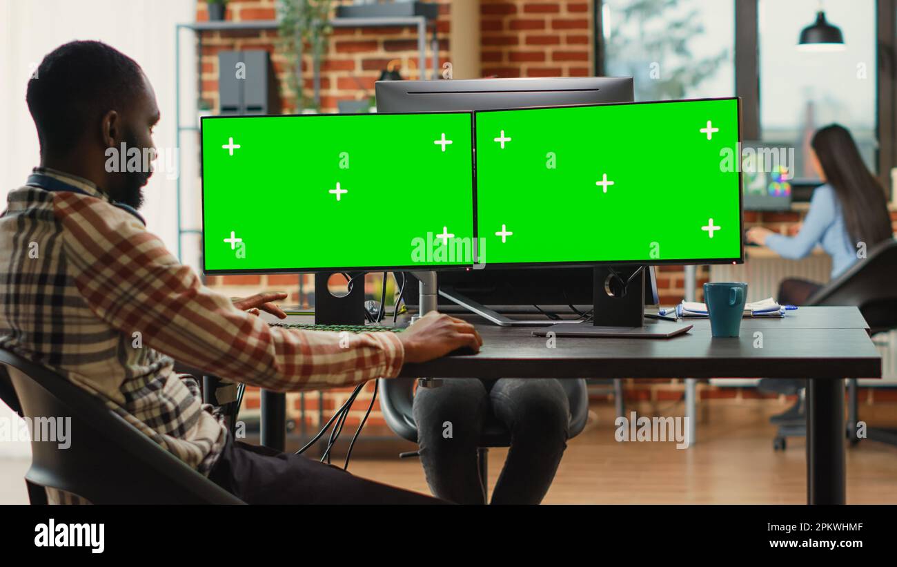 Professional IT expert analyzing greenscreen on multiple monitors ...