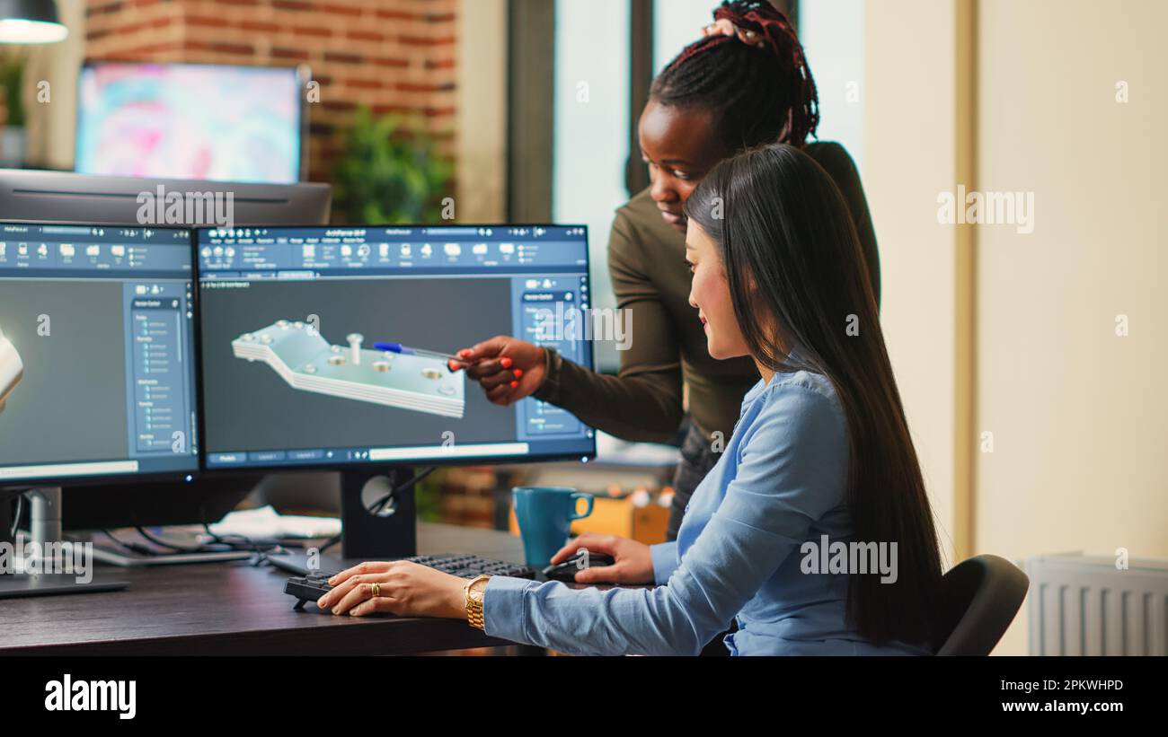 Female engineers analyzing clamp component prototype, working with industrial 3d software. Team ...