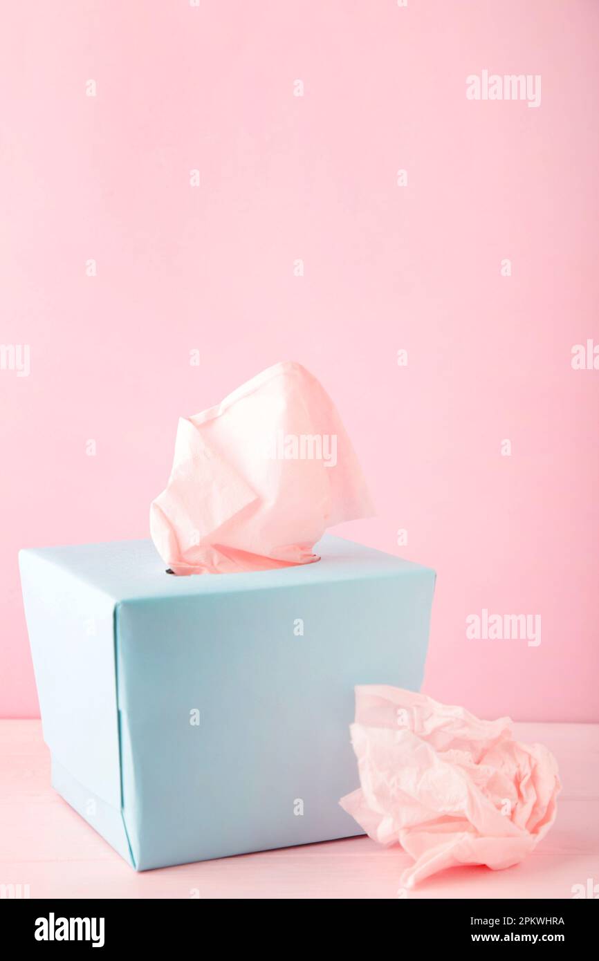 Blue box with paper tissues and used crumpled napkins on pink ...