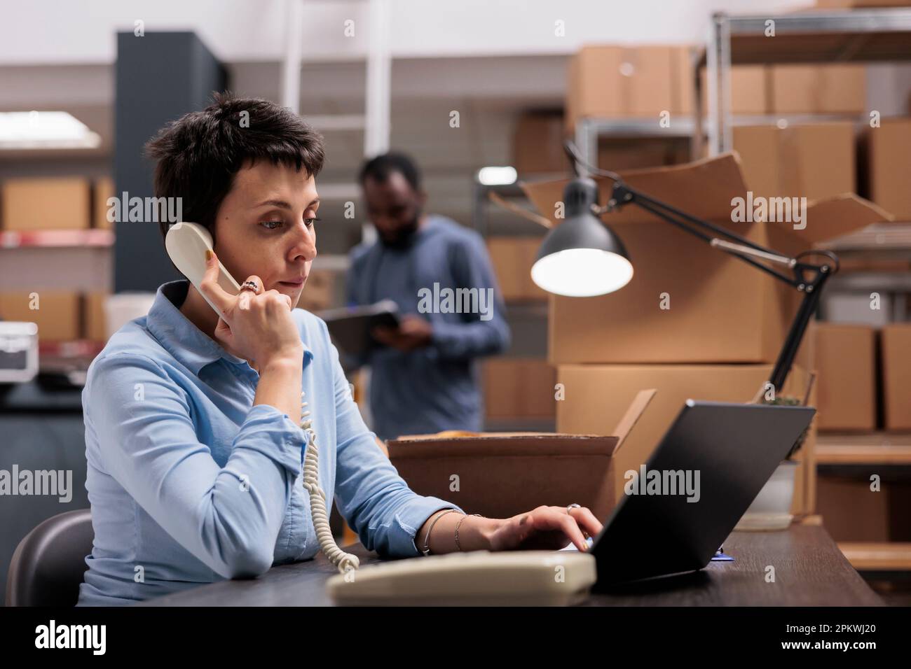 Storehouse manager talking at landline phone with remote supervisor ...
