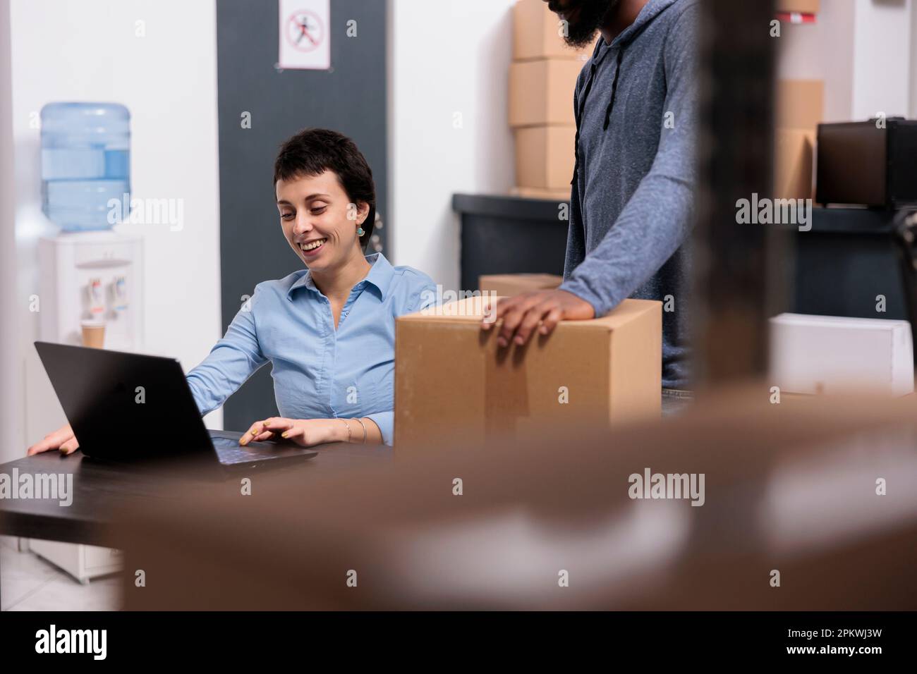 Storehouse workers looking at shipping logistics on laptop computer ...