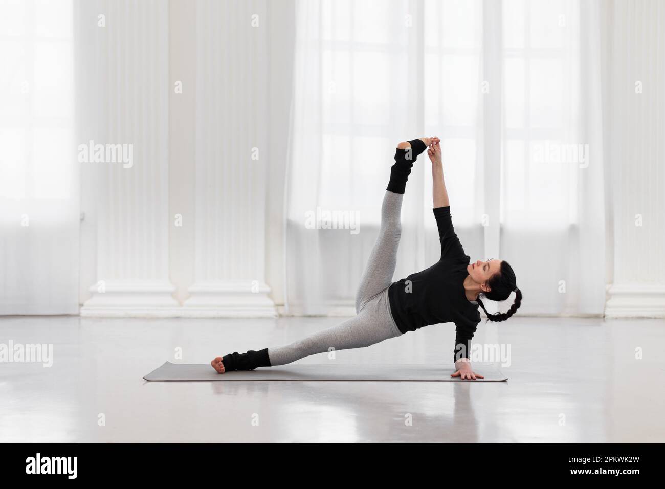 Charming young woman doing vertical splits during yoga class in a cozy ...