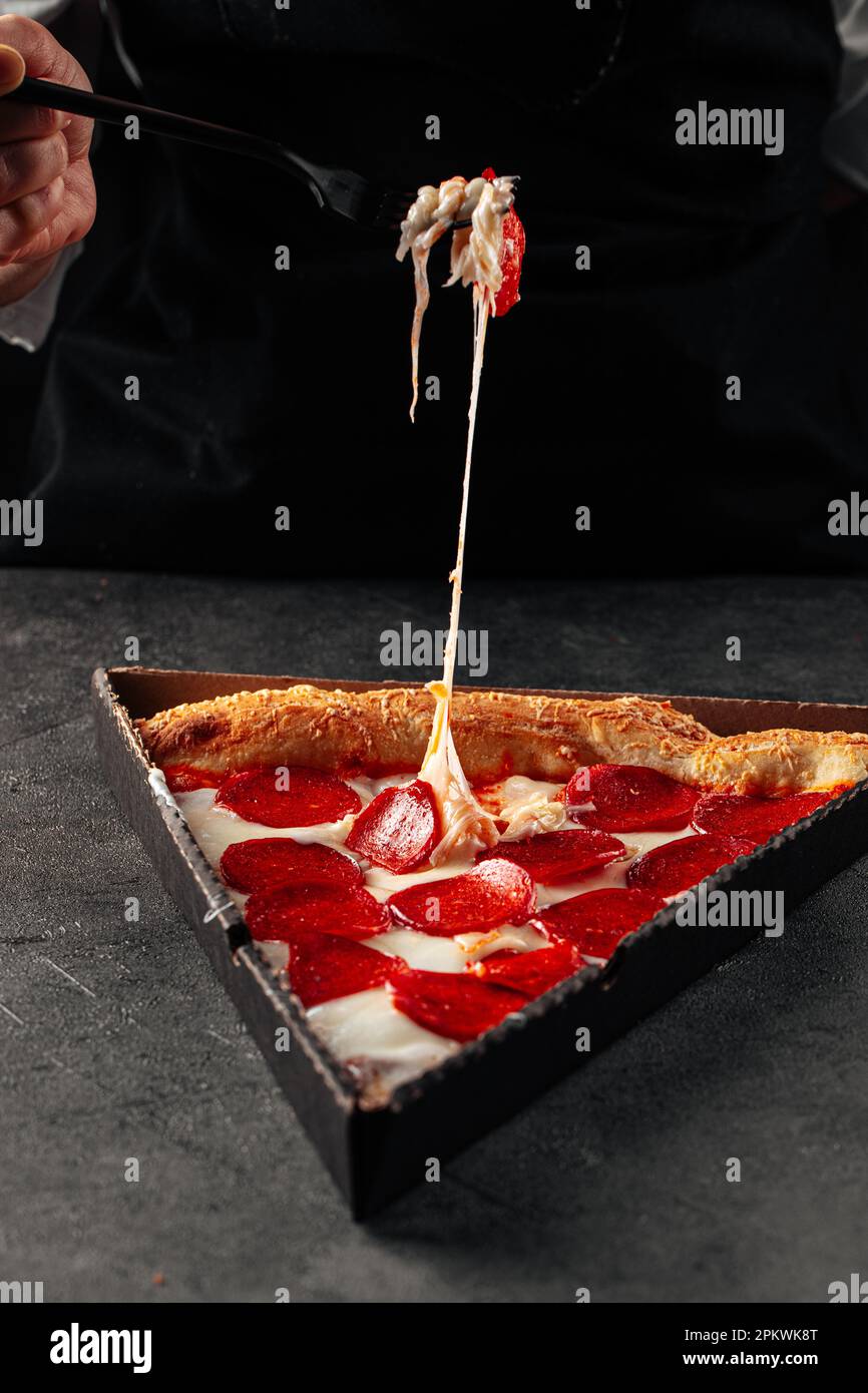 Pulling cheese from slice of pepperoni pizza Stock Photo - Alamy