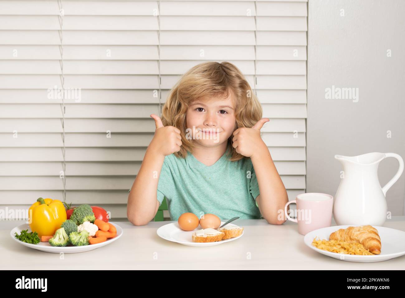 Kid boy eating healthy food vegetables. Breakfast with milk, fruits and ...