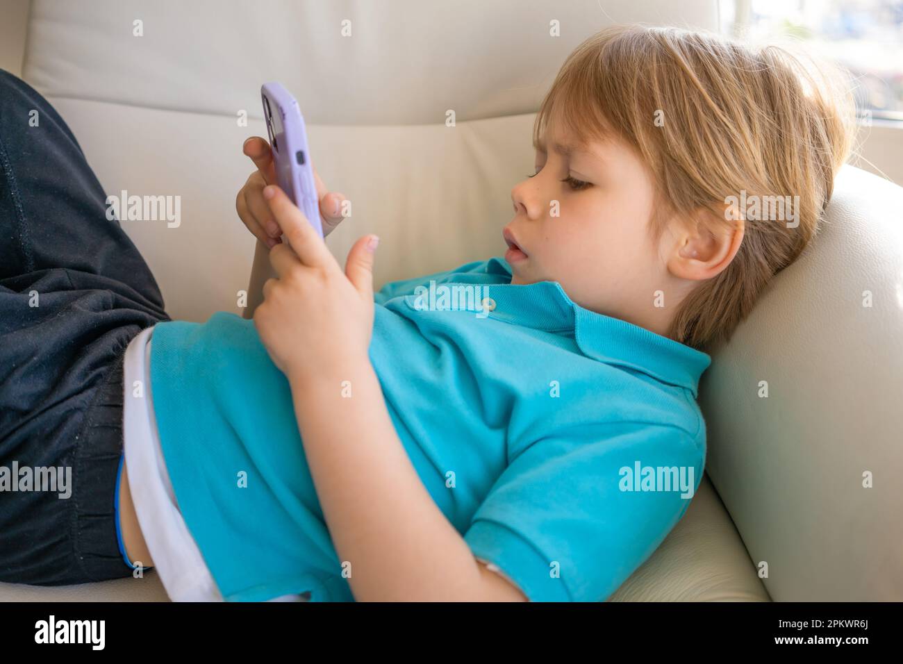 Close up cute little boy using smartphone, looking at screen, curious ...