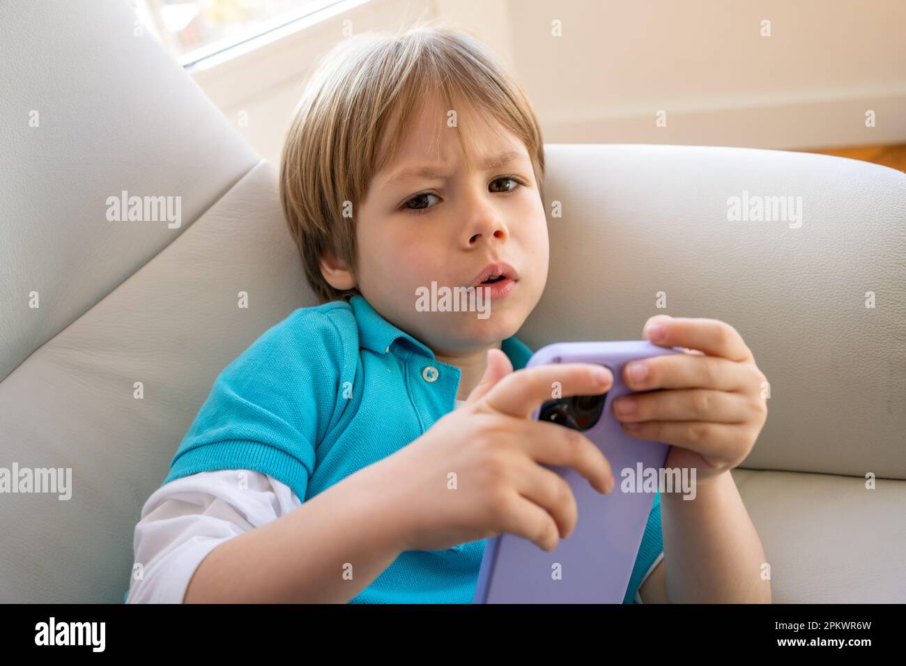Close up cute little boy using smartphone, looking at screen, curious ...