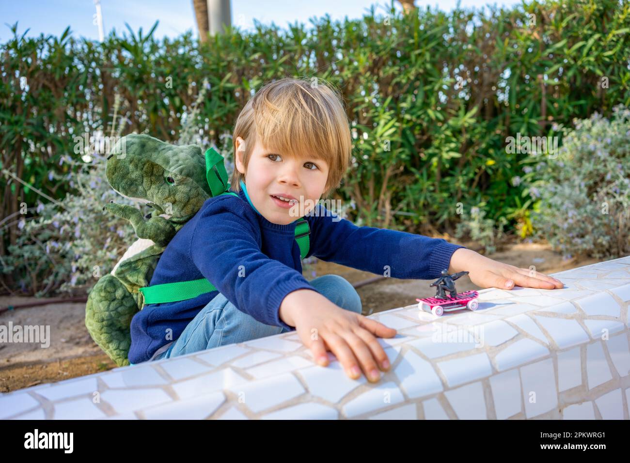 Child on spring nature background. Sweet, happy child boy playing upside down on a grass in a ...