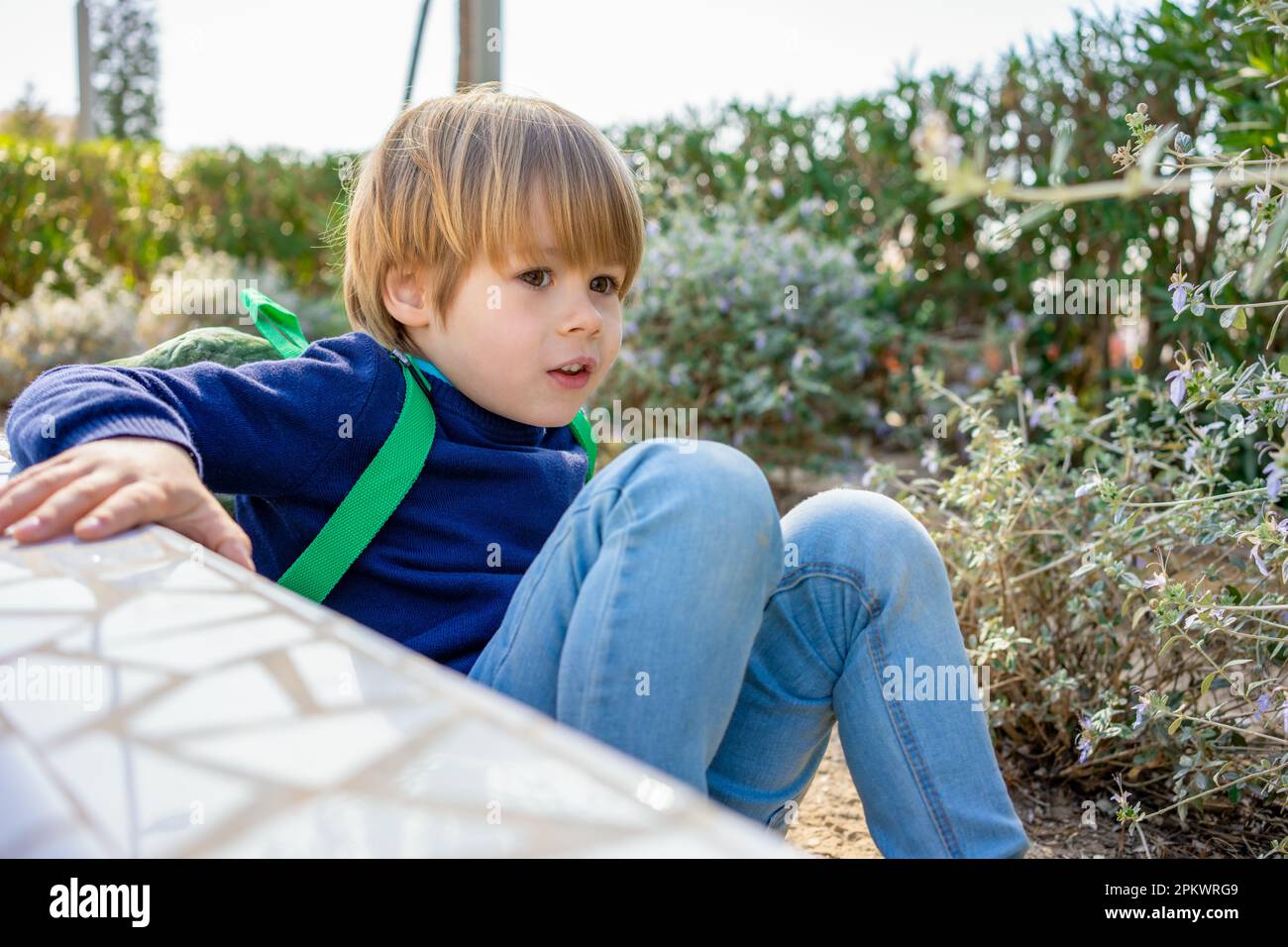 Child on spring nature background. Sweet, happy child boy playing upside down on a grass in a ...