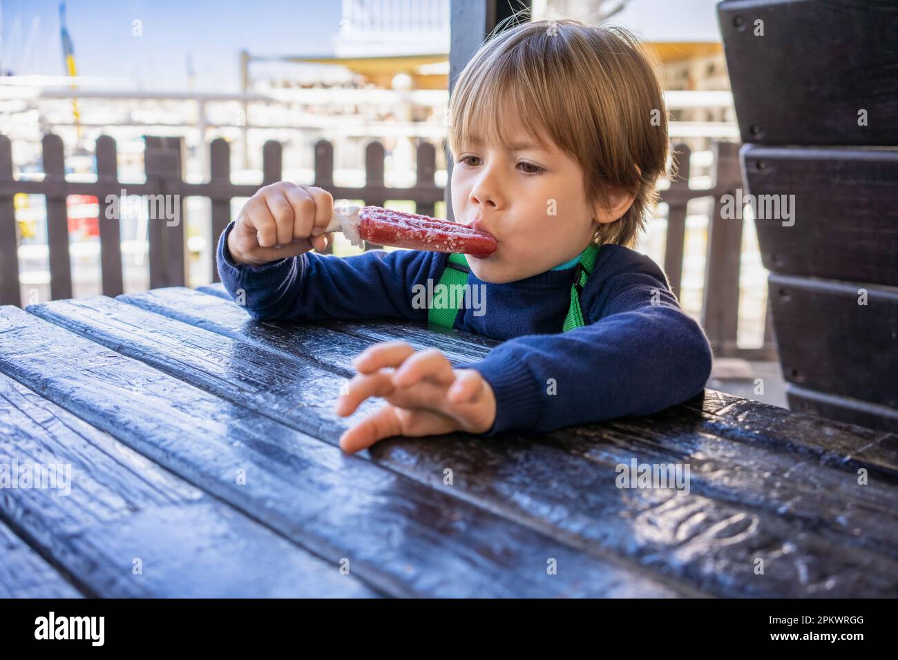 Little adorable boy sitting outdoors and eating ice cream. Kid enjoy a ...