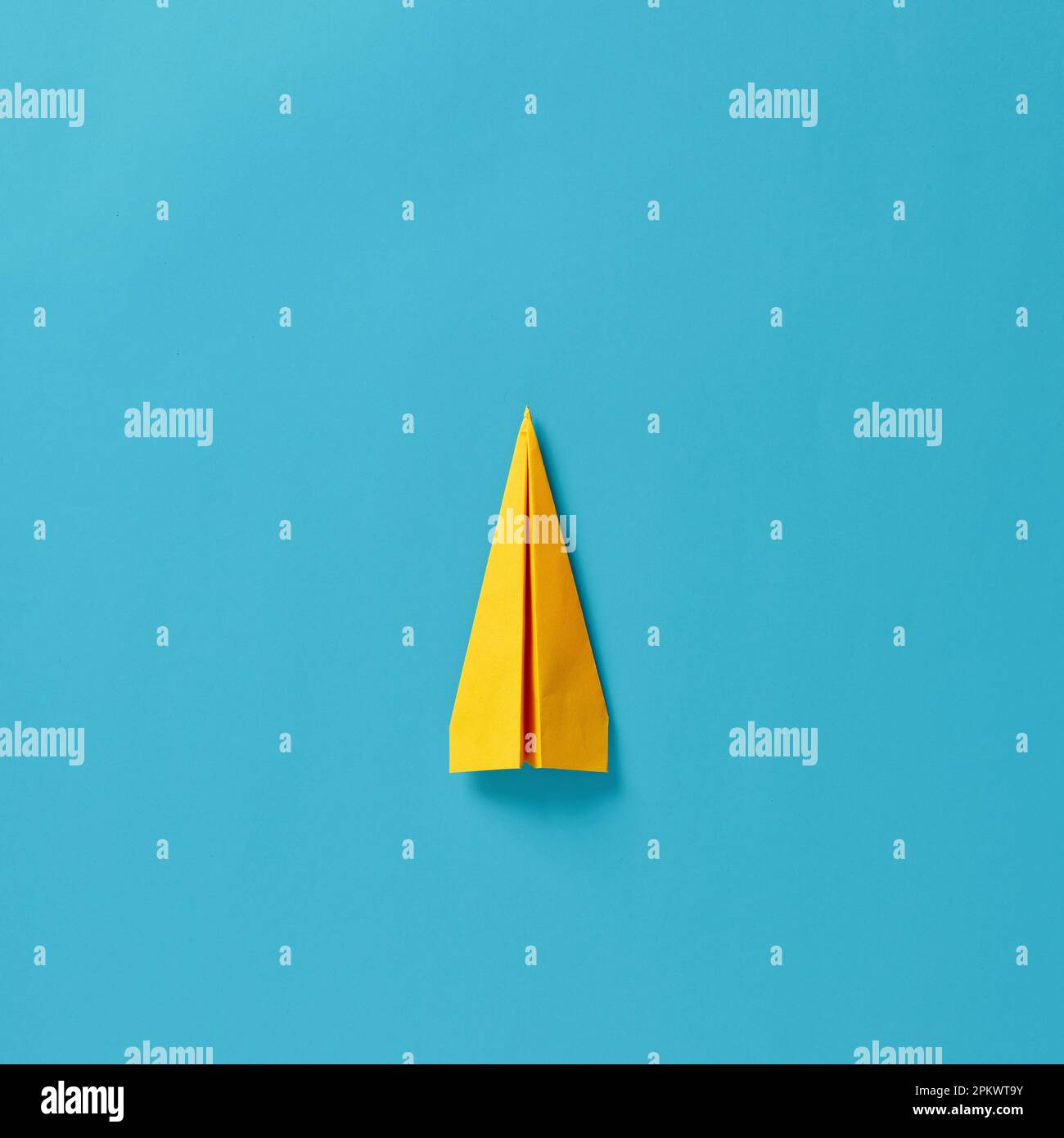 Yellow paper airplane on blue background. Top view Stock Photo - Alamy