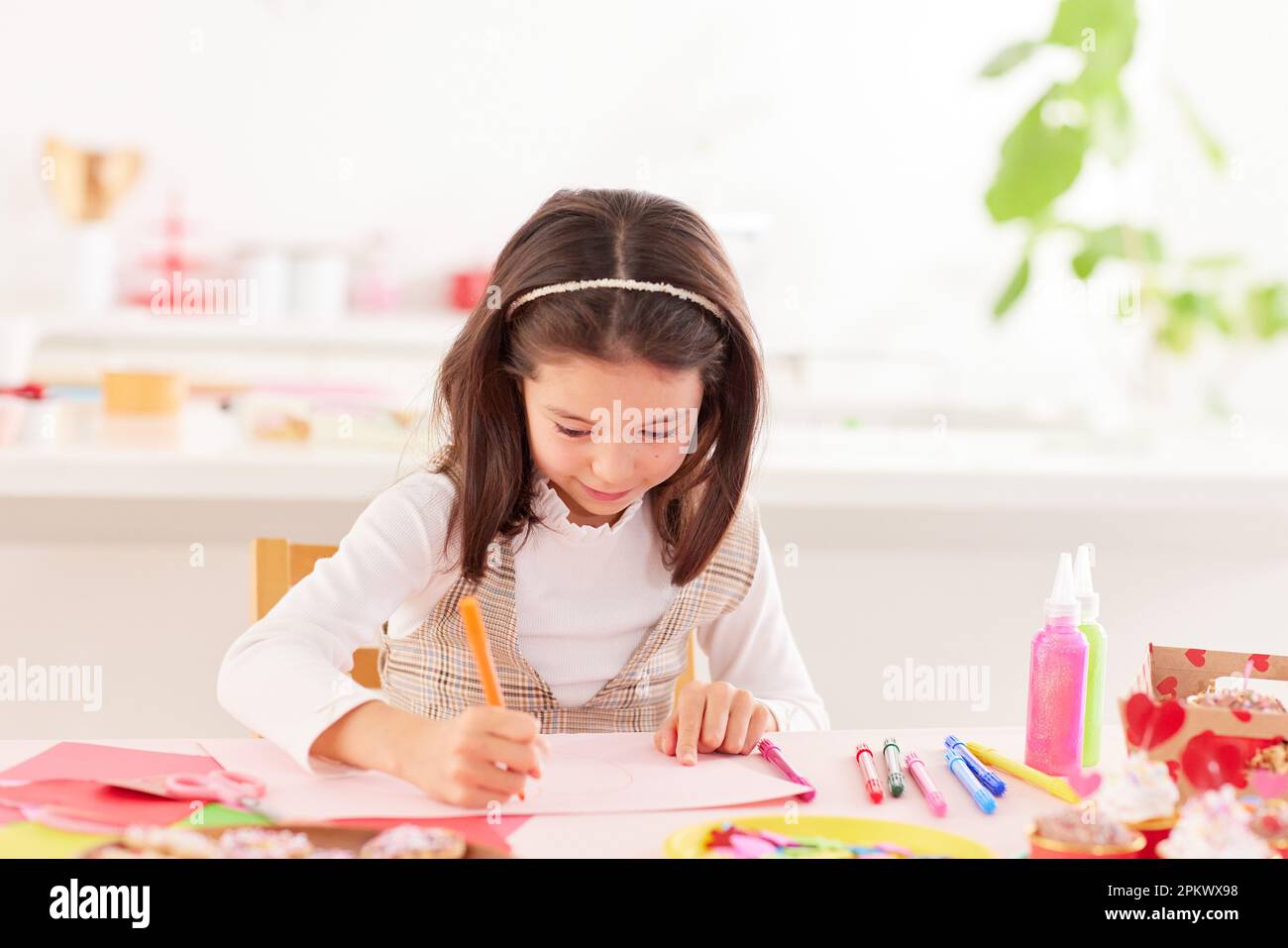 Smiling young girl playing with craft paper Stock Photo - Alamy