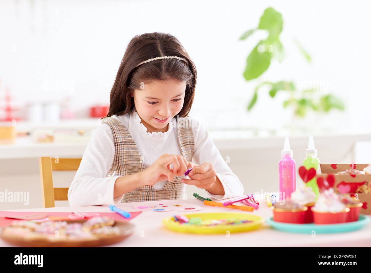 Smiling young girl playing with craft paper Stock Photo - Alamy