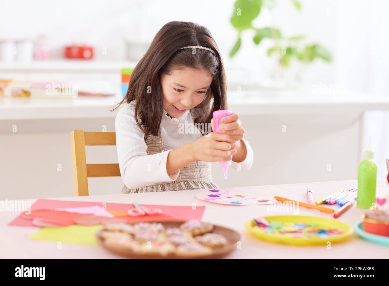 Smiling young girl playing with craft paper Stock Photo - Alamy
