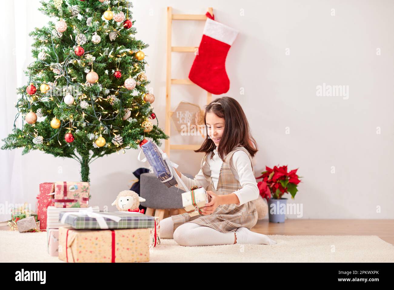 Smiling young girl opening Christmas presents Stock Photo - Alamy