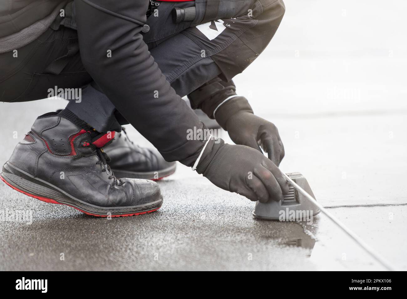 Ground wire. A worker lays a ground cable on the roof of a building ...