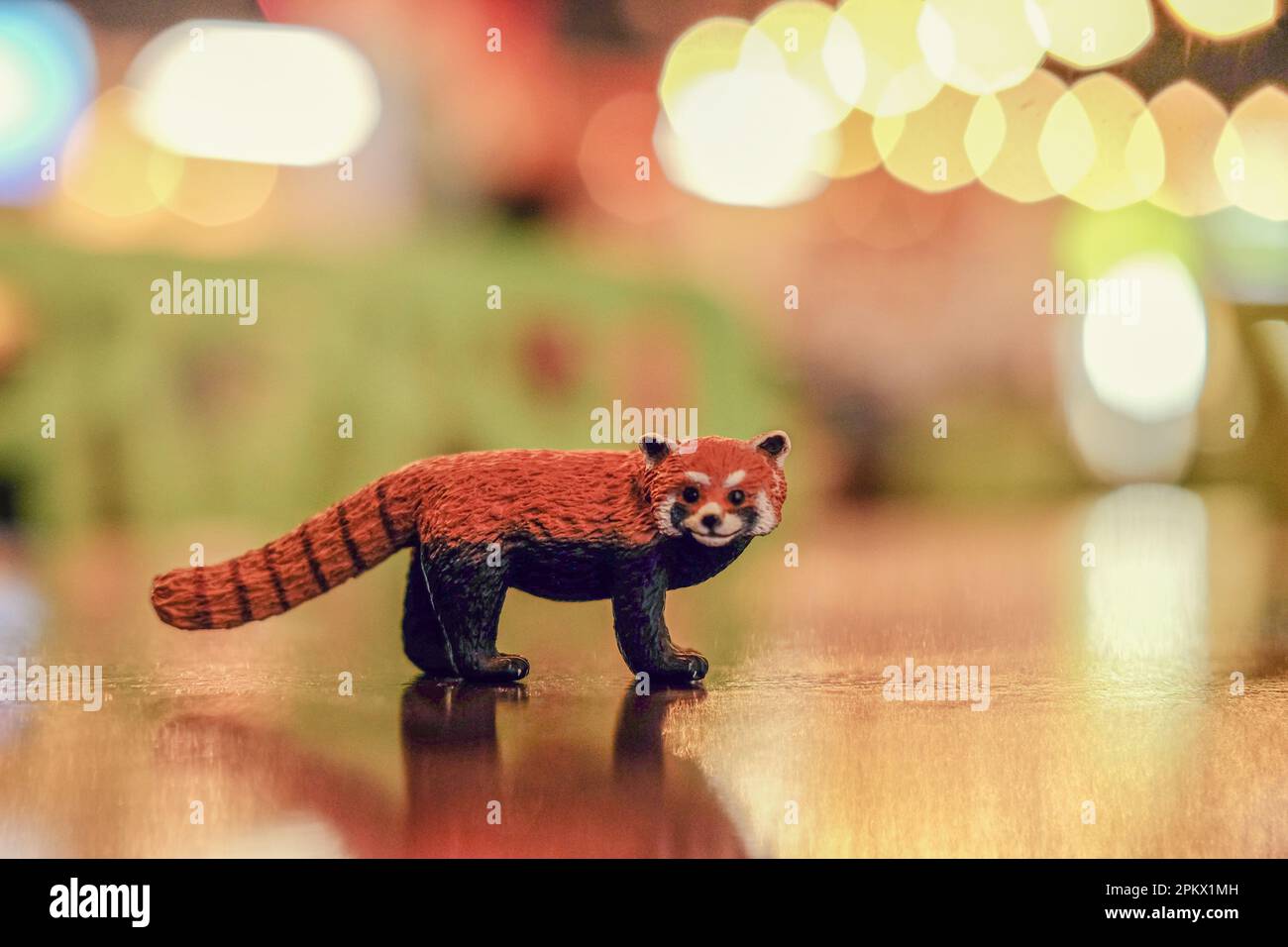 Red panda toy animal in a dim room on a table with bokeh background ...