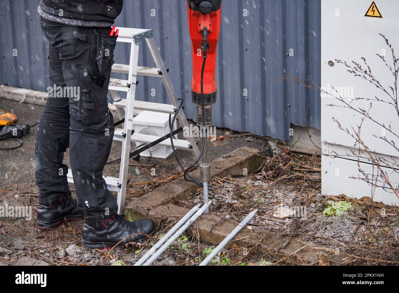 A worker installs a ground rod to ground a building. A worker in work ...