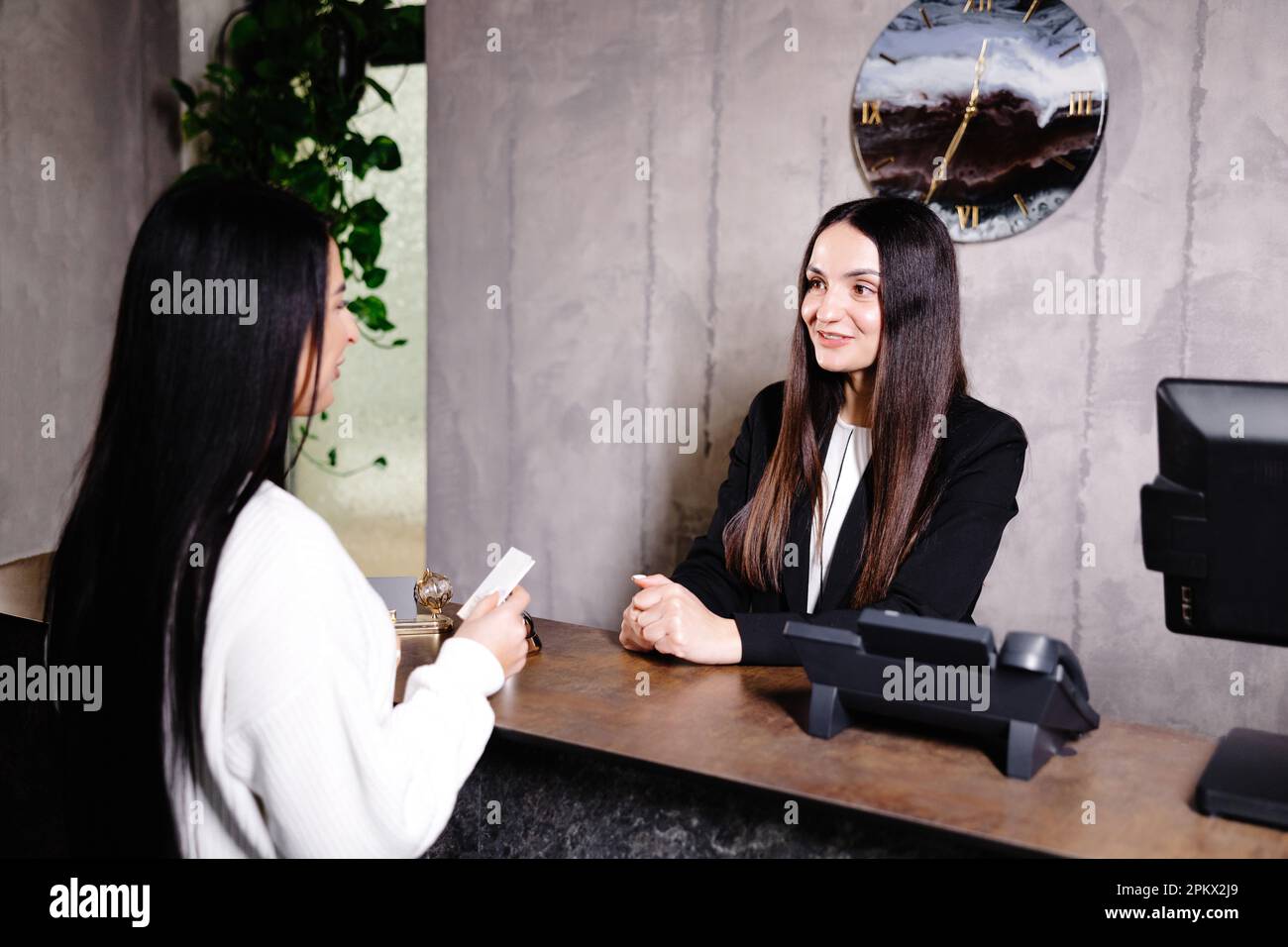 Friendly young concierge standing behind a reception counter giving ...