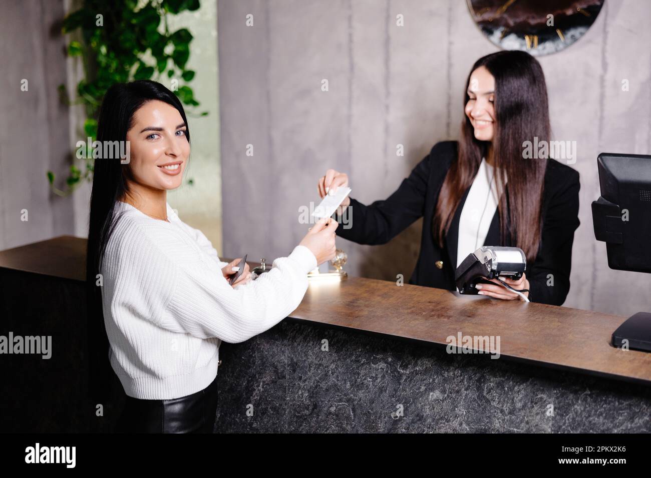 Friendly young concierge standing behind a reception counter giving ...