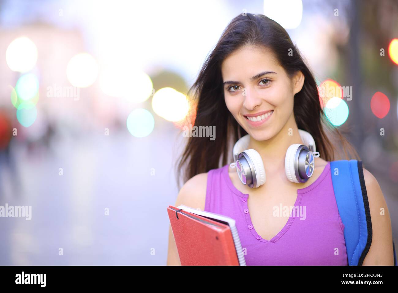 Front view portrait of a happy student posing in the street looking at ...