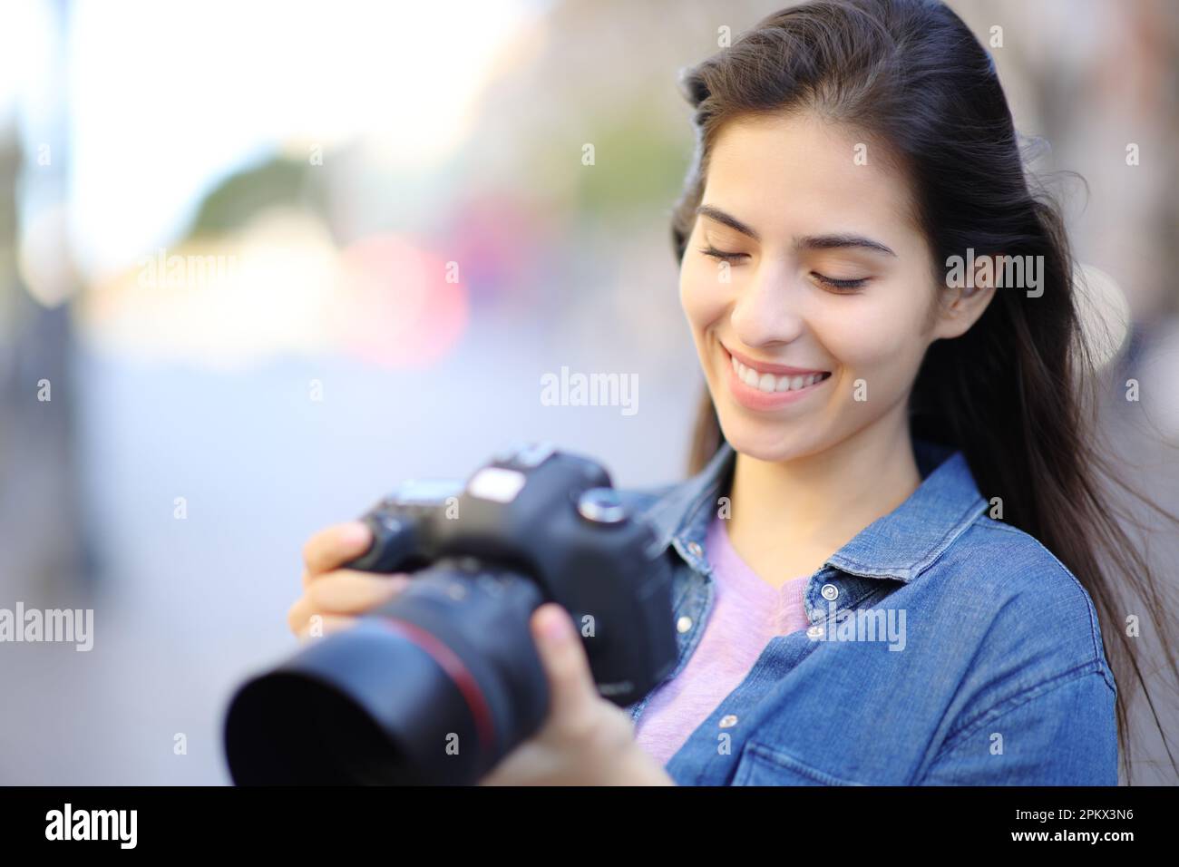 Happy photographer checking photos on camera outdoor in the street ...
