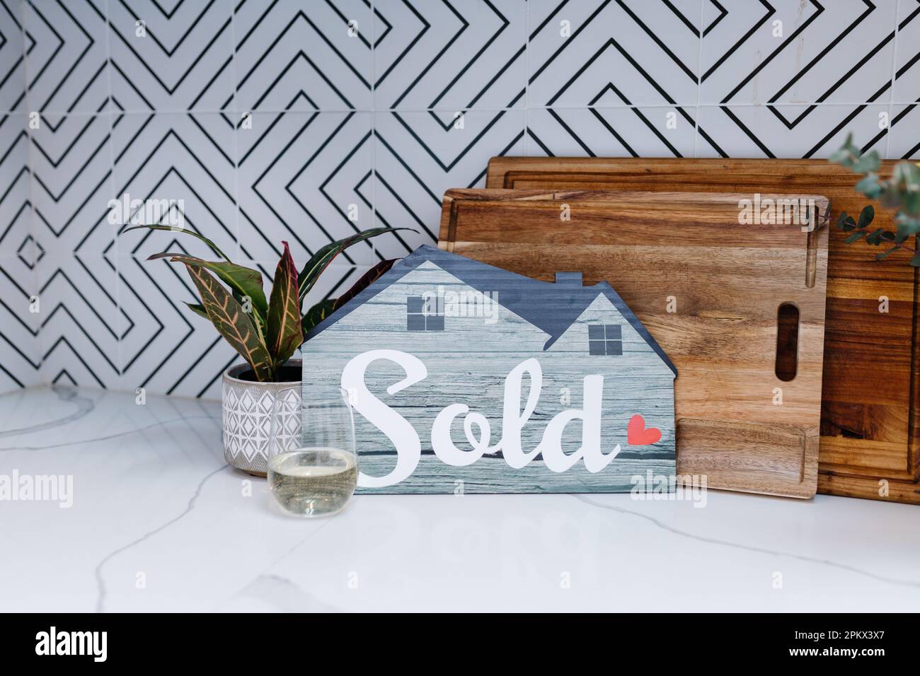 Sold sign shaped as a house in kitchen with wooden cutting boards Stock ...