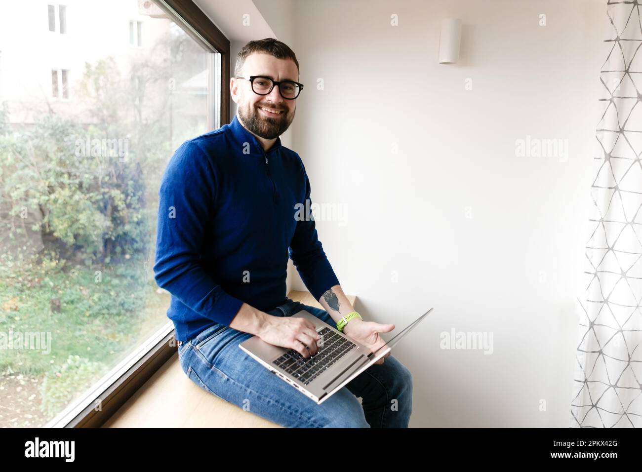 man in blue sweater and jeans is working alone at home with laptop ...