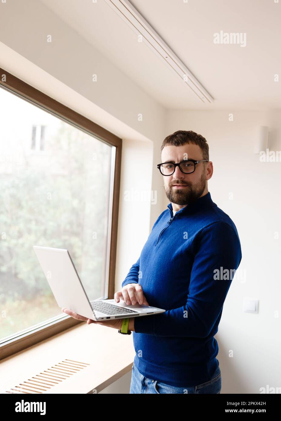 man in blue sweater and jeans is working alone at home with laptop ...