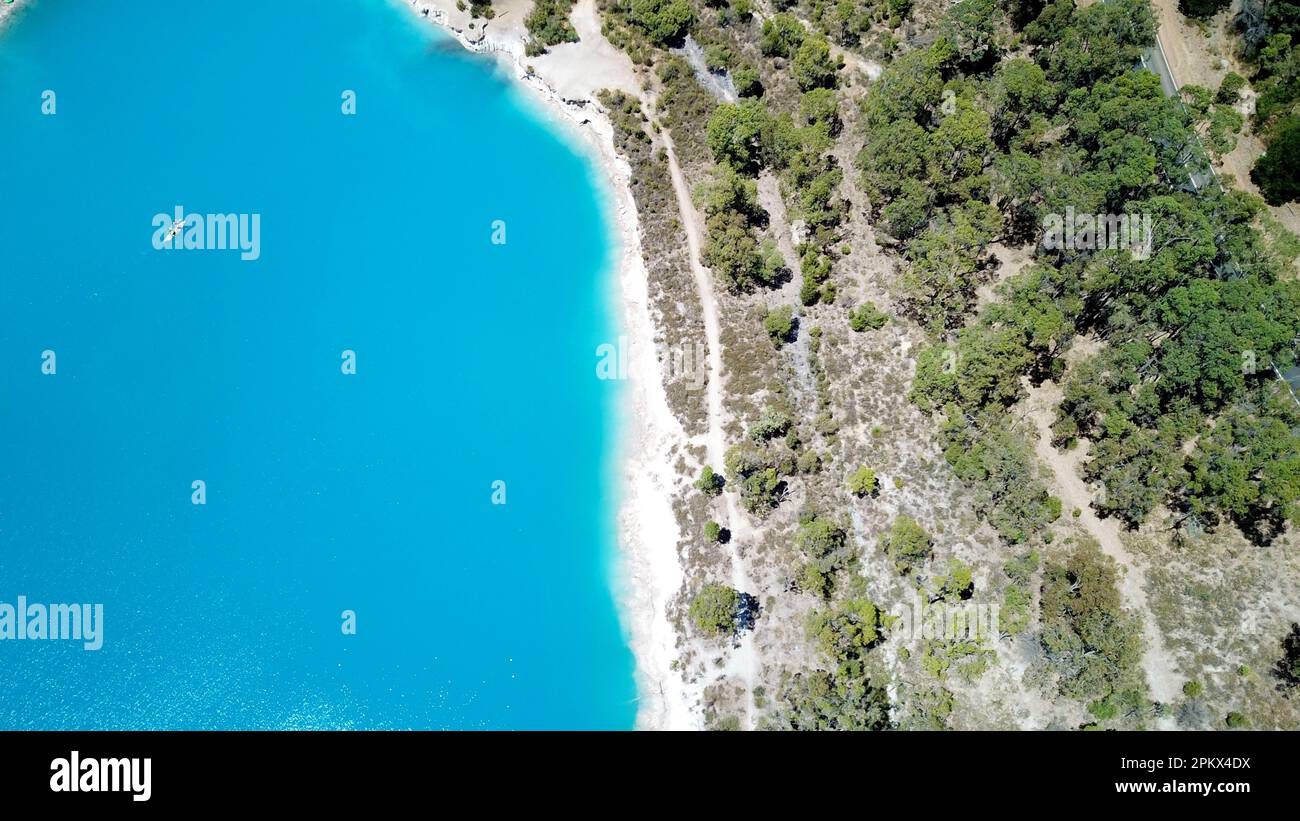 Aerial view of a blue lake and bush with a stand up board in the water ...