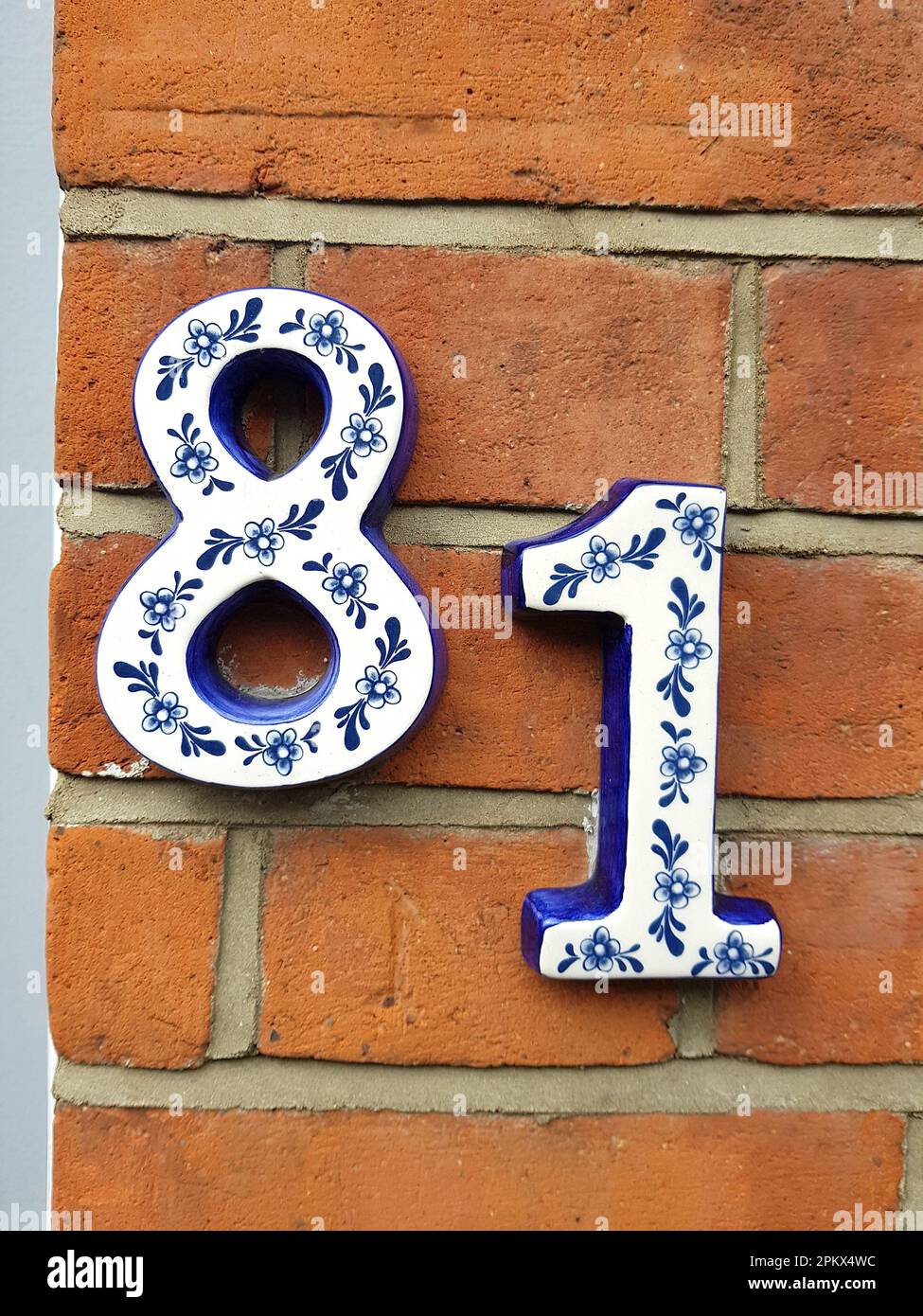 The number 8i decorated with blue flowers on a red brick wall Stock ...