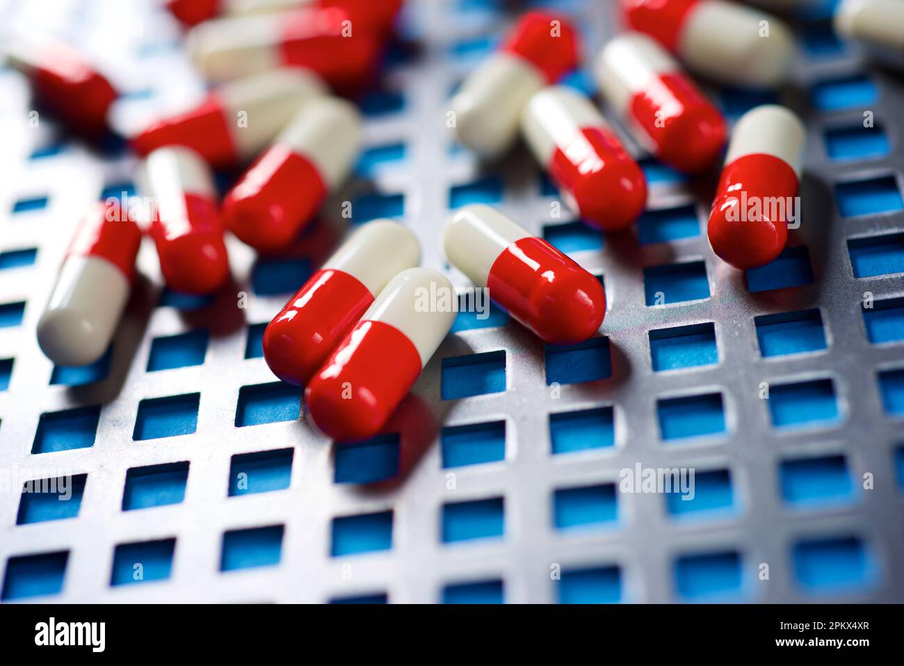Red and white pills on a metal grid Stock Photo - Alamy