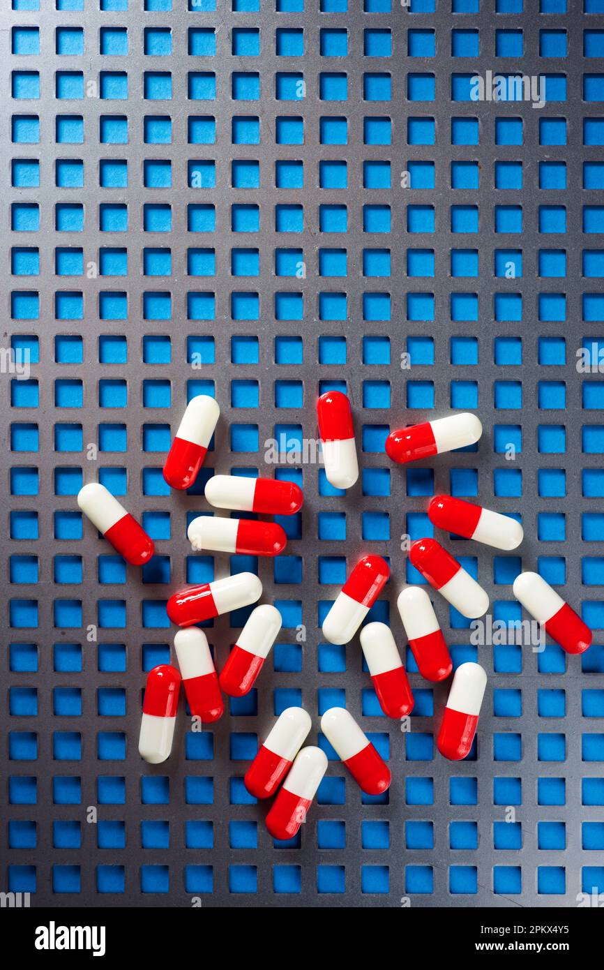 Red and white pills on a metal grid Stock Photo - Alamy