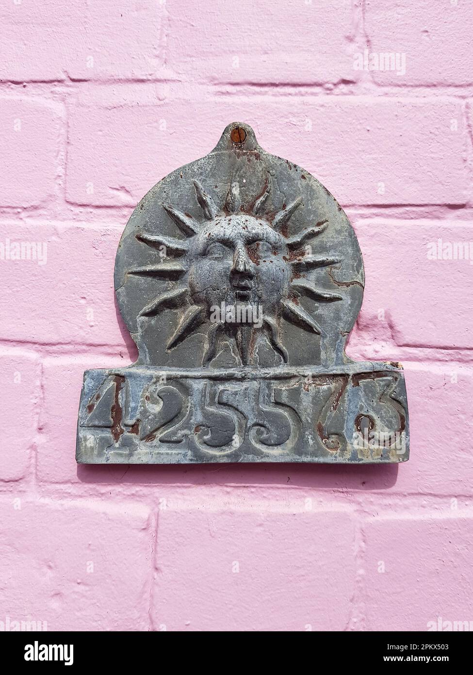 Old metal sun emblem on a pink brick wall Stock Photo - Alamy