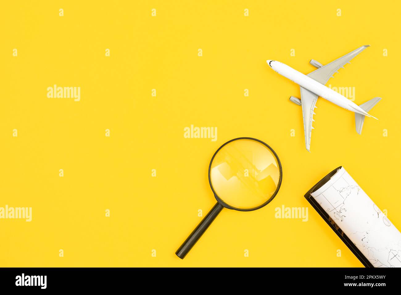 Airplane model, map and magnifier on yellow background, flat lay Stock ...