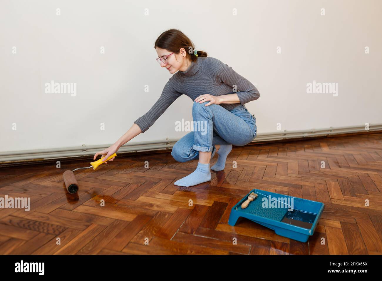 woman in the process of varnishing the floor during the renovation ...