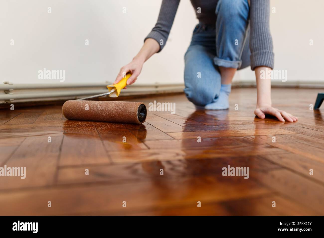 woman in the process of varnishing the floor during the renovation ...