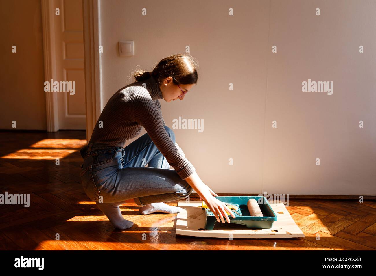 woman in the process of varnishing the floor during the renovation ...