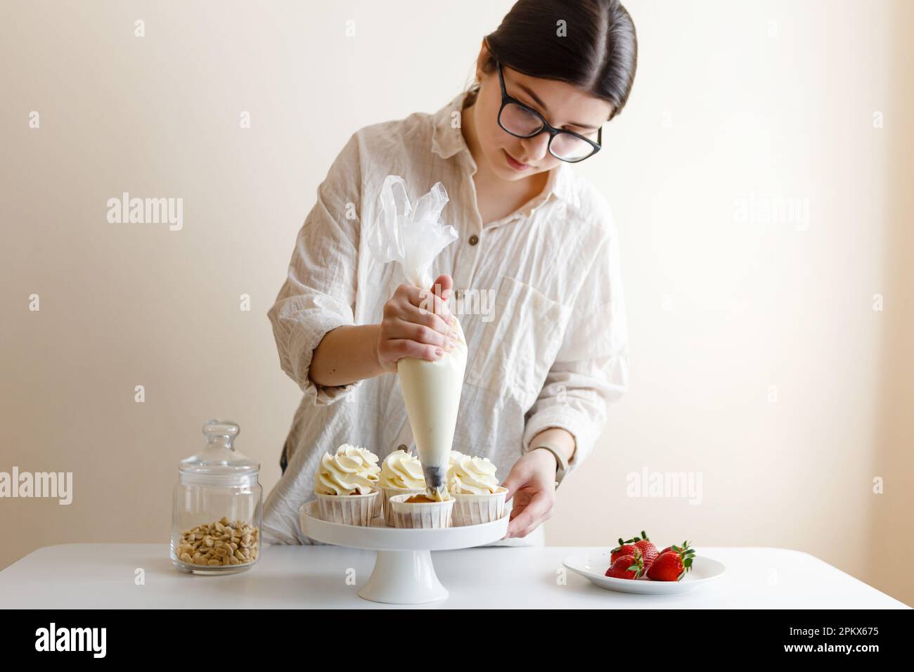 pastry chef girl prepares cupcakes with cream in the kitchen Stock ...