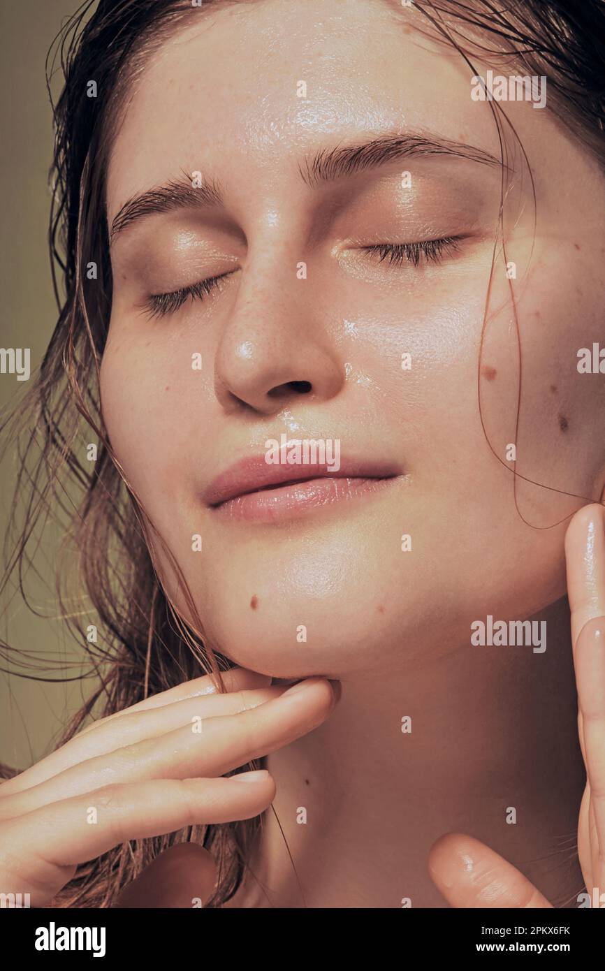 Close up model with hydrated facial skin and natural makeup on green ...