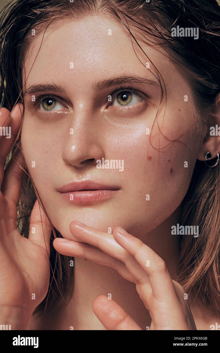 Close up model with hydrated facial skin and natural makeup on green ...