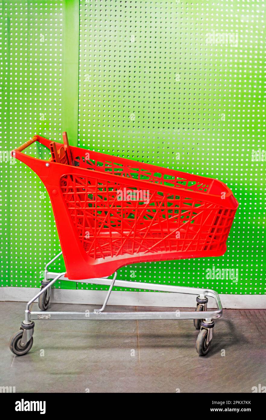 red cart for groceries in the mall on near the green wall. vertical ...