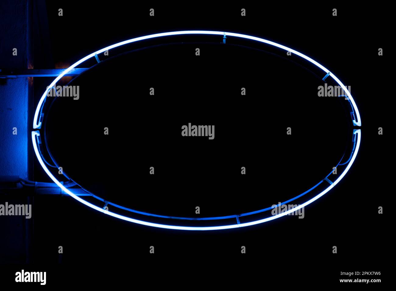 Close up on an oval shaped blue neon light attached to the wall on its ...