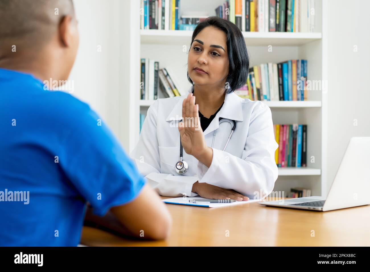 Hispanic female doctor talking about cancer with patient at hospital ...