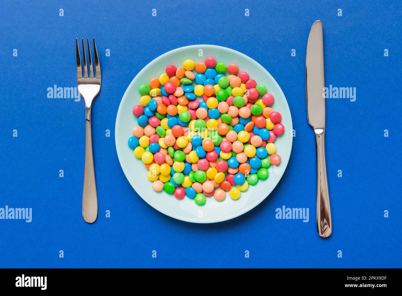 cutlery on table and sweet plate of candy. Health and obesity concept ...