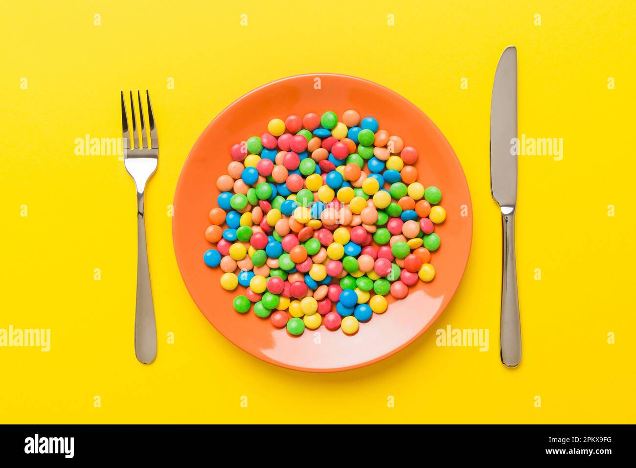 cutlery on table and sweet plate of candy. Health and obesity concept ...