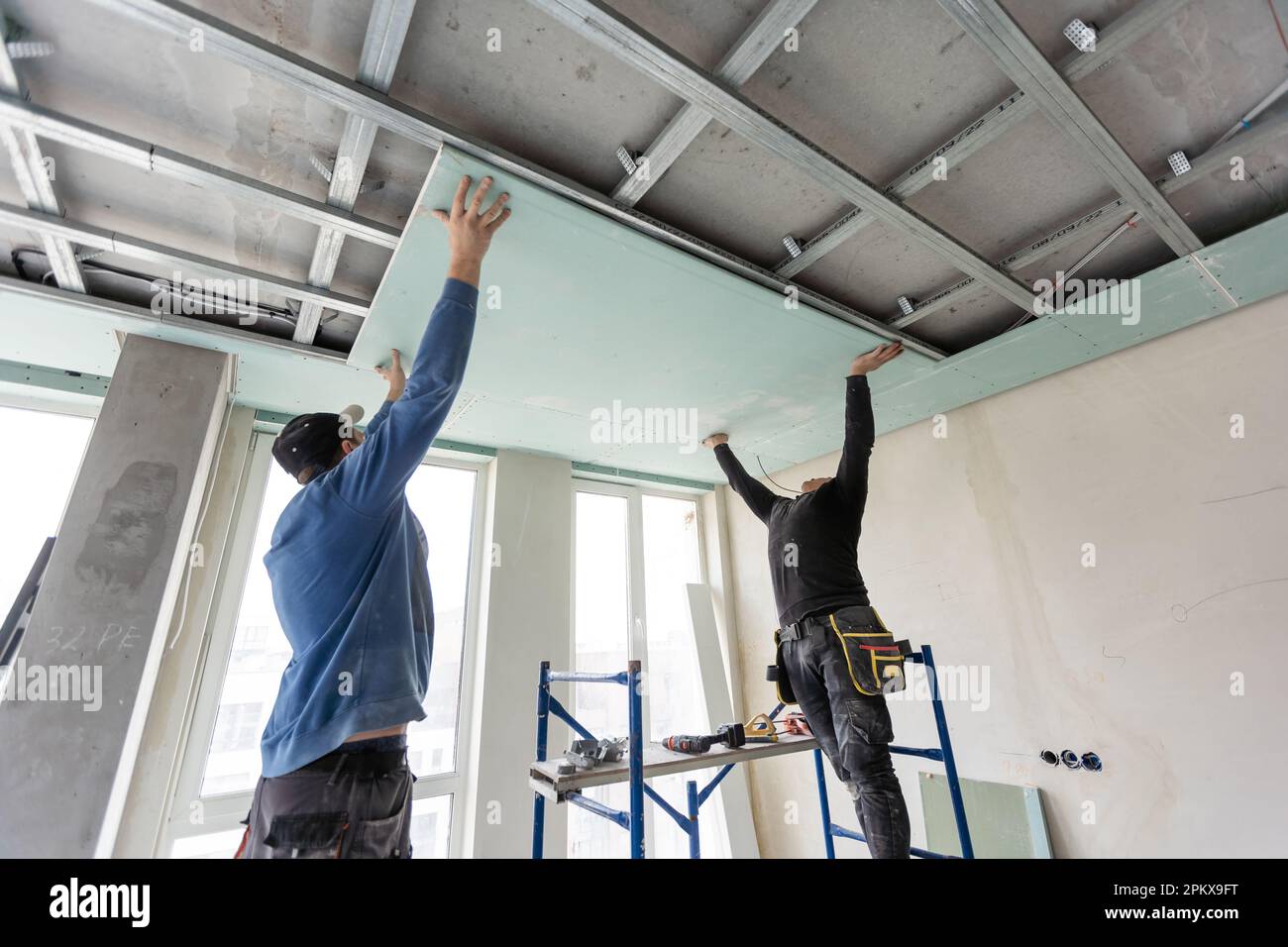 Workers fitting panel into frame of ceiling Stock Photo - Alamy