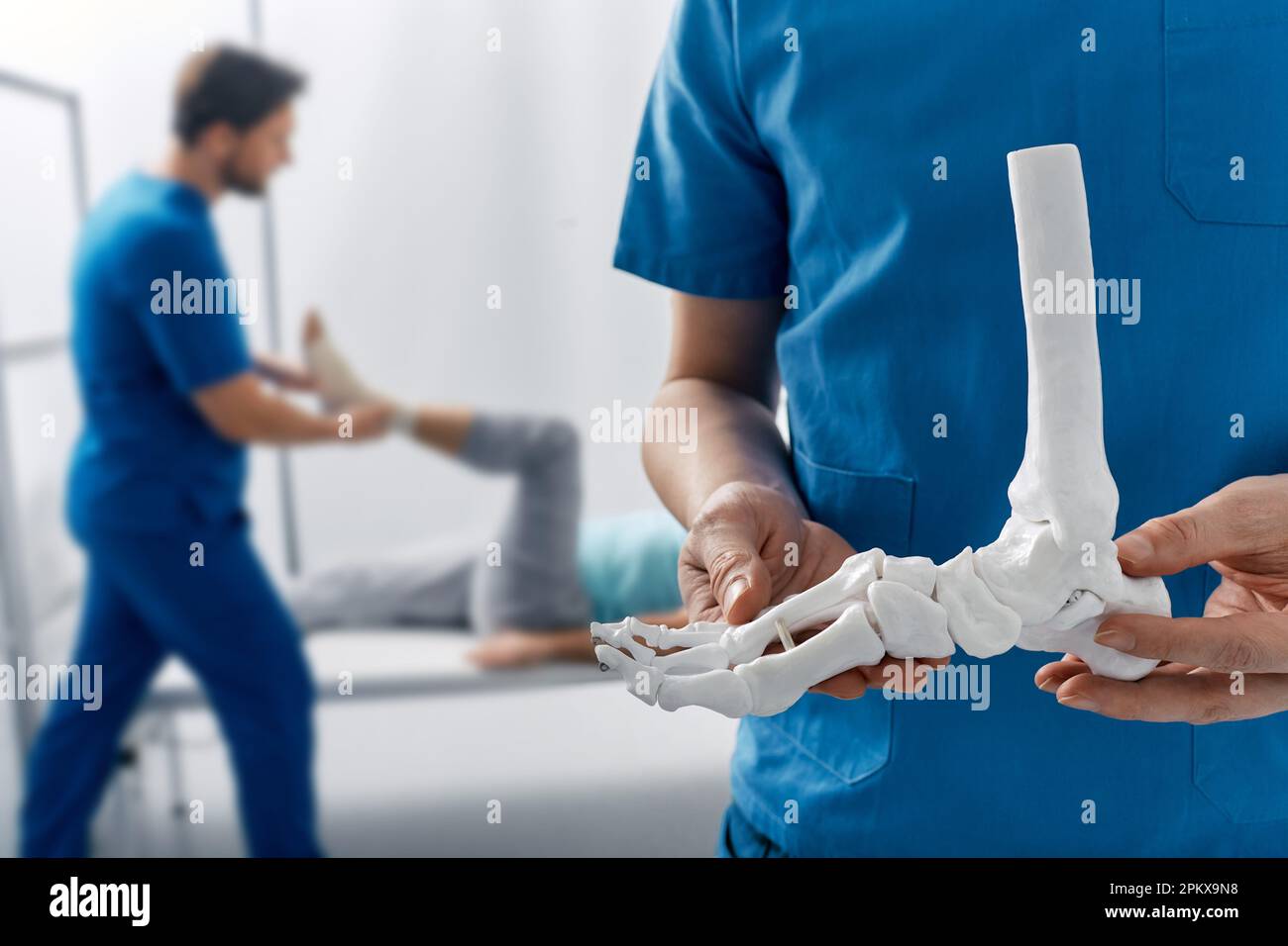 Podiatrist showing anatomical foot skeleton model during his assistant ...