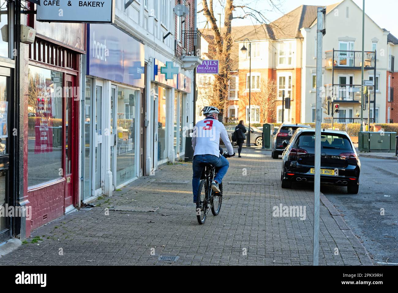 An elderly male cyclist riding a bike on the pavement with cars also ...